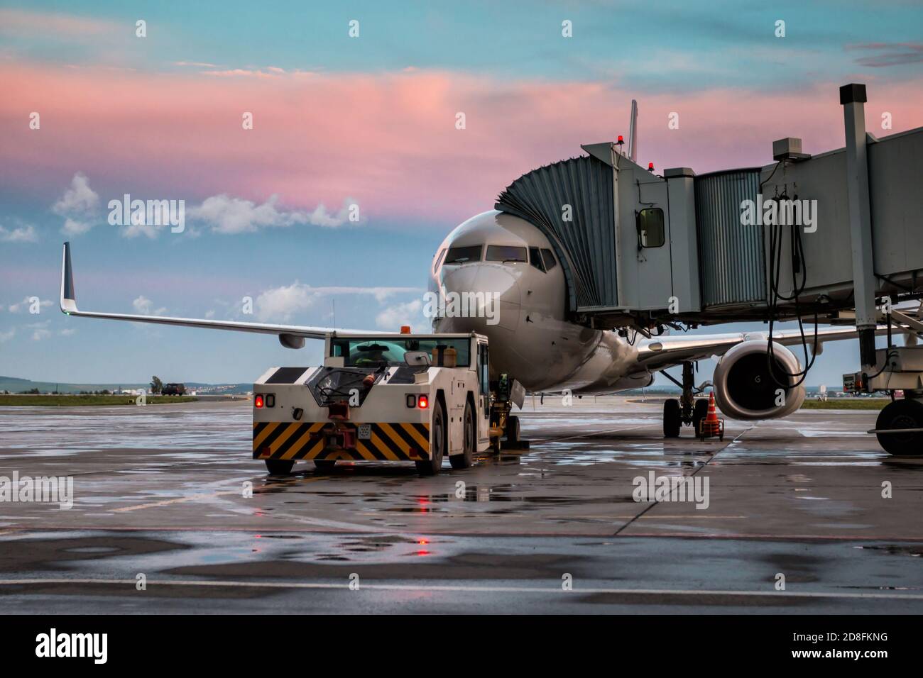 Passenger airplane and tow truck at the jet bridge. Front view Stock ...