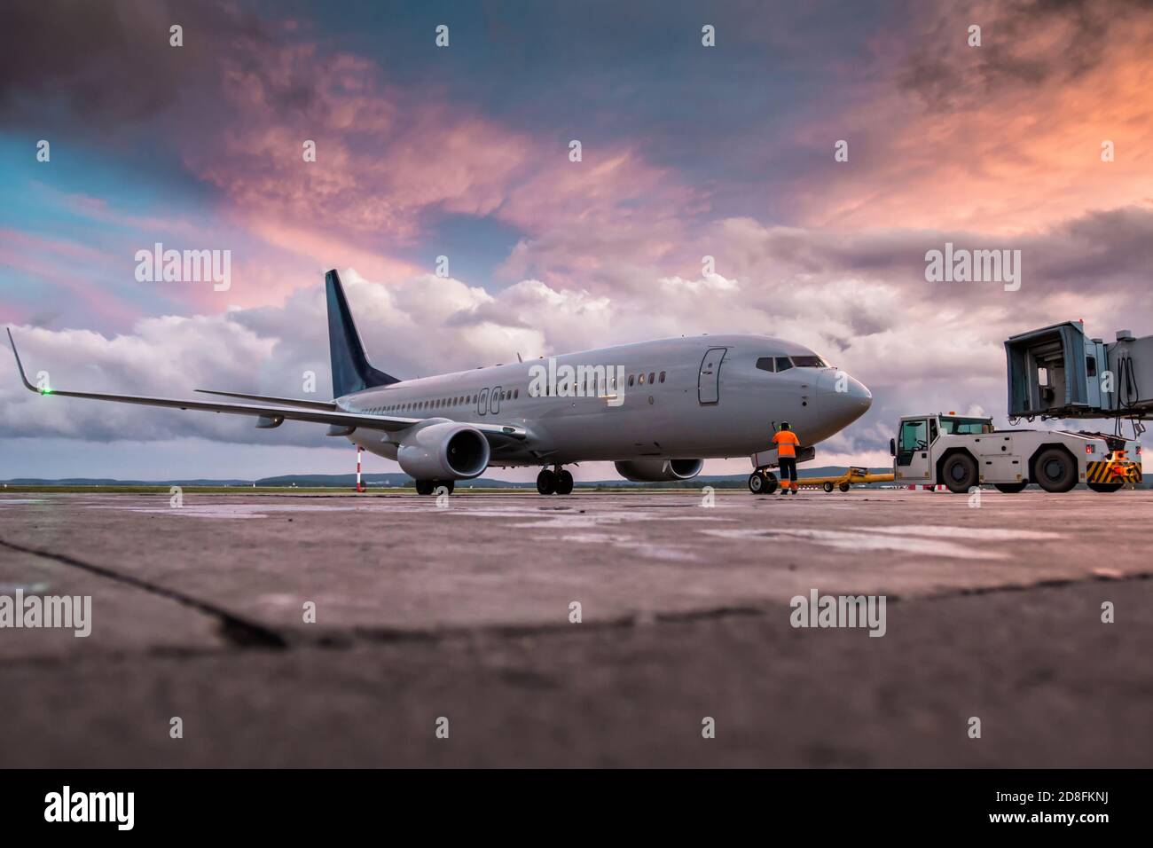 Tow tractor pushes passenger aircraft from boarding bridge Stock Photo ...
