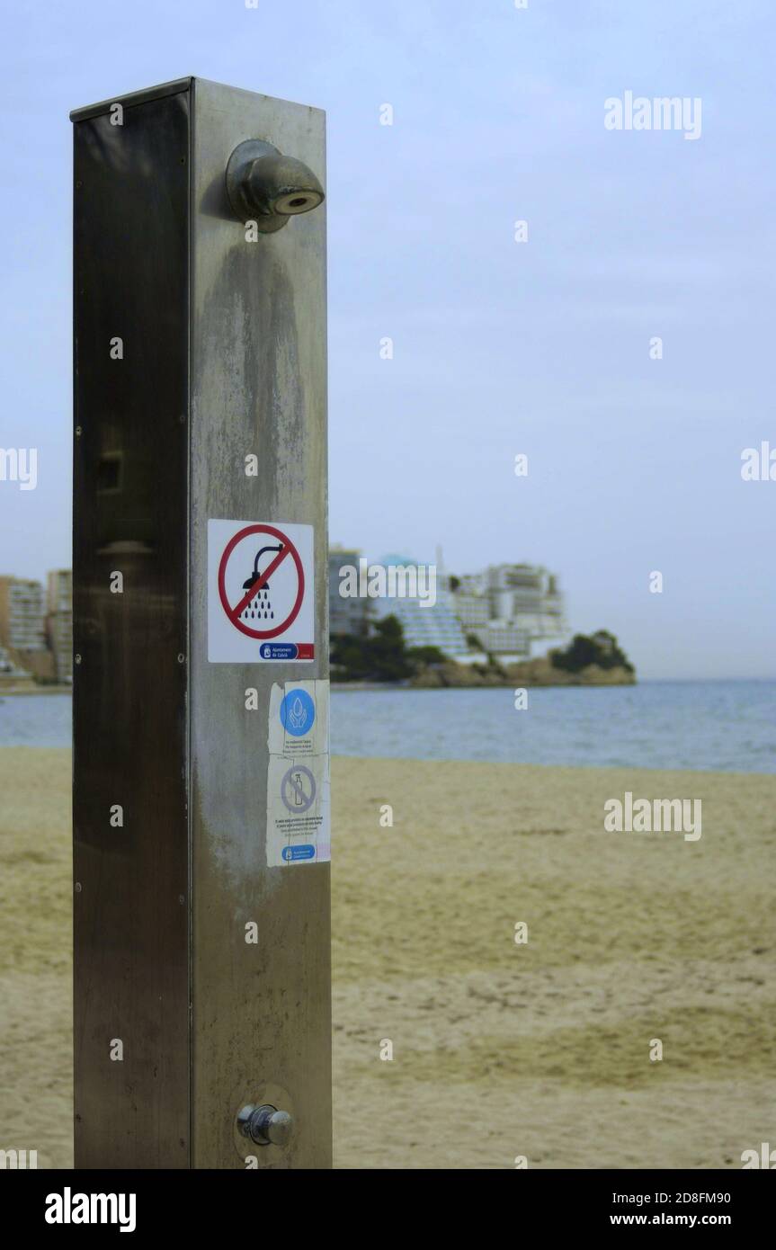 Vertical shot of a water shower at the beach with a ''no shower'' sign ...