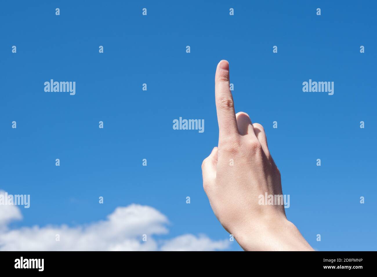 Close-up female hand with index finger up on a background of blue sky ...