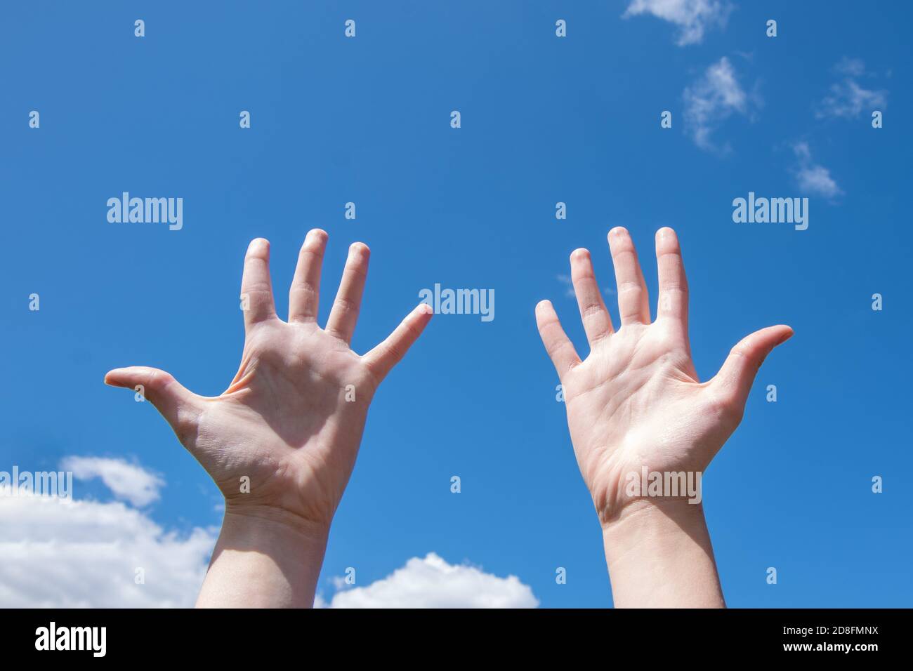 Close-up of female hands, empty open palms on a background of blue sky ...