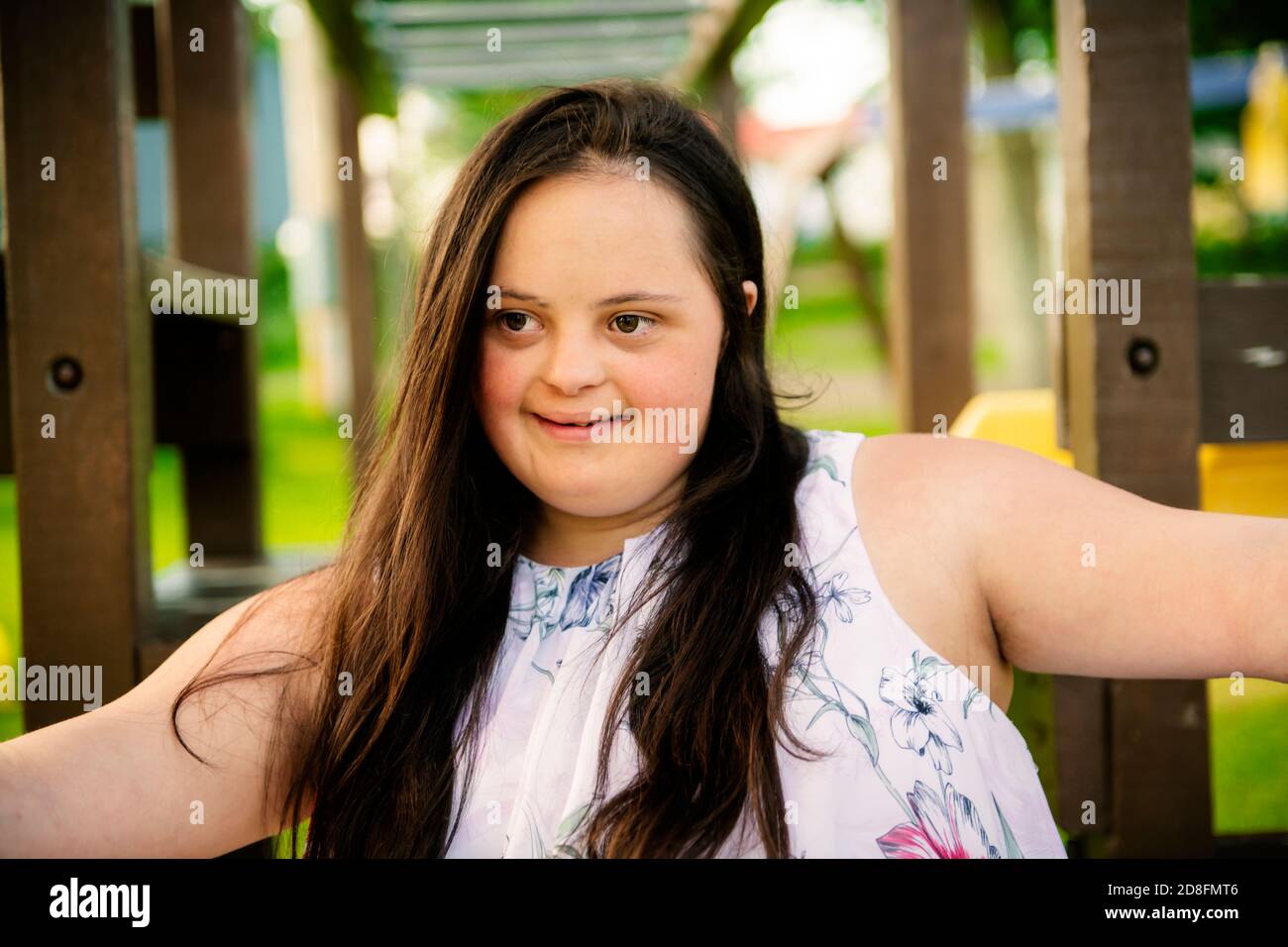 A portrait of trisomie 21 adult girl outside at sunset having fun on a ...