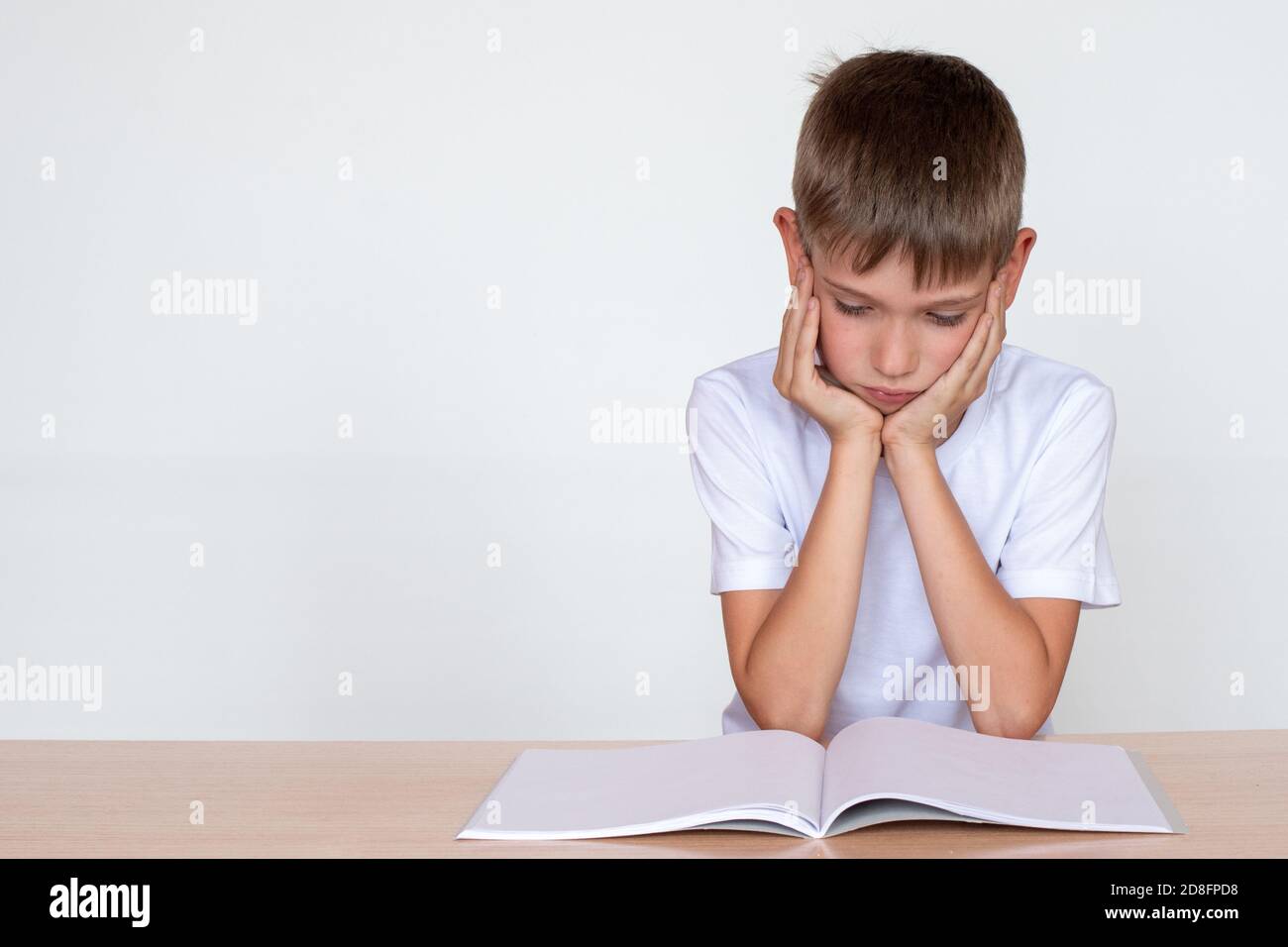 Back to school. Thinking child boy looking in a notebook or book ...