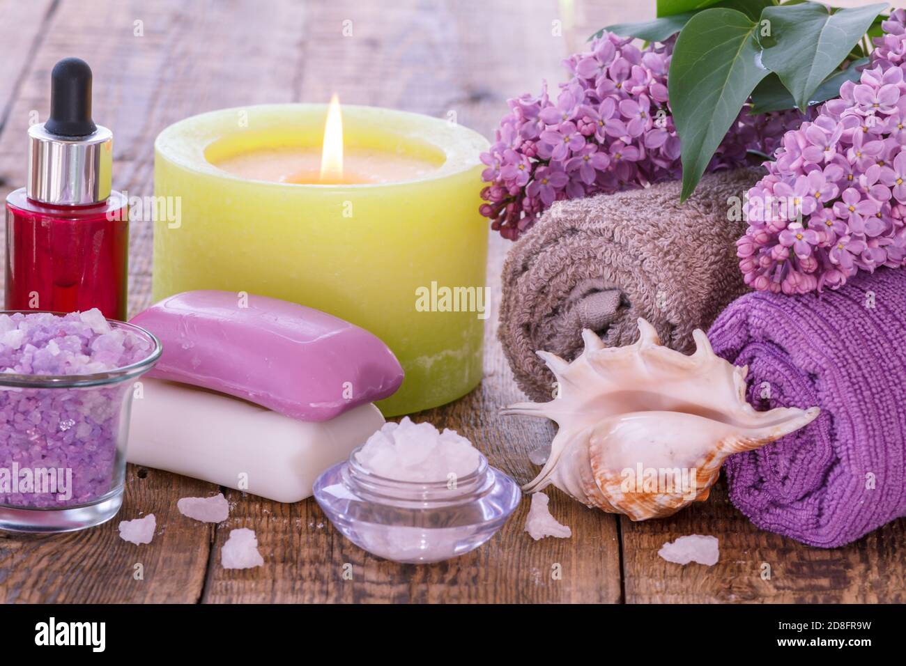 Soap, red bottle with aromatic oil, burning candle, bowls with sea salt ...
