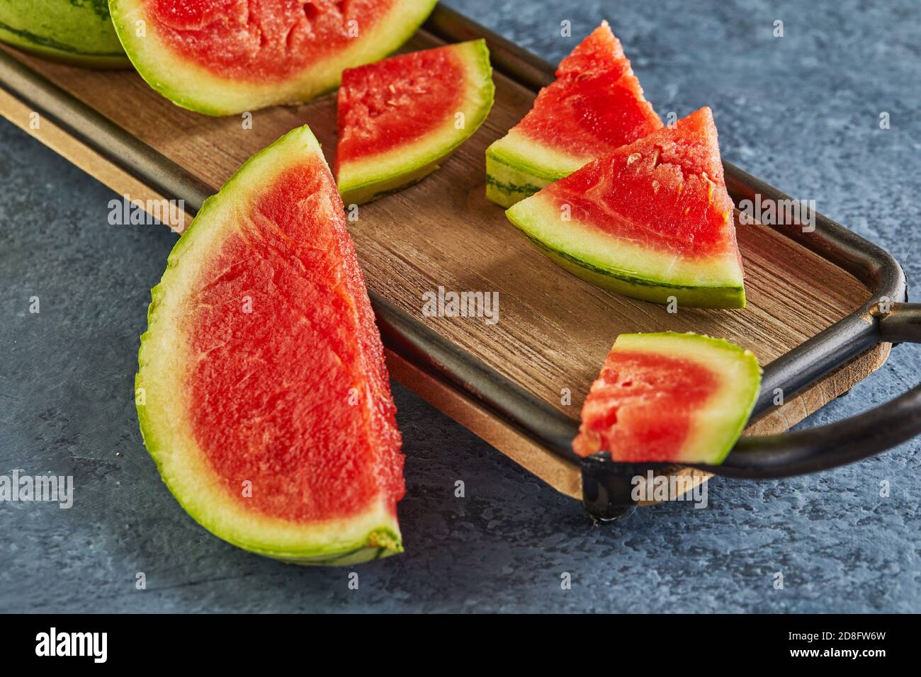 Mini Watermelon with sliced wedges on a wooden stand on a blue ...