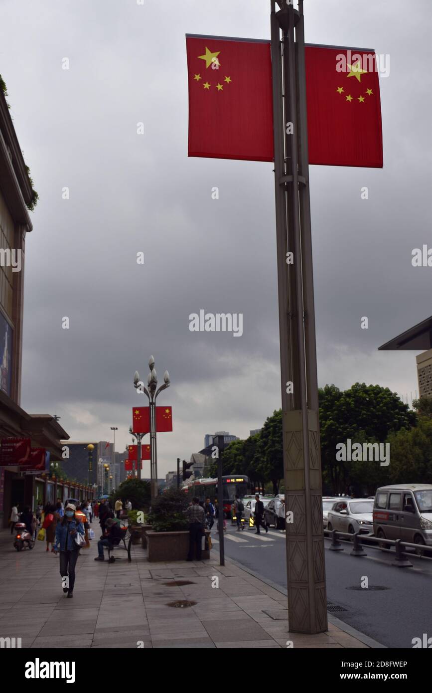 National flags fly on the street, under which vehicles and pedestrians ...