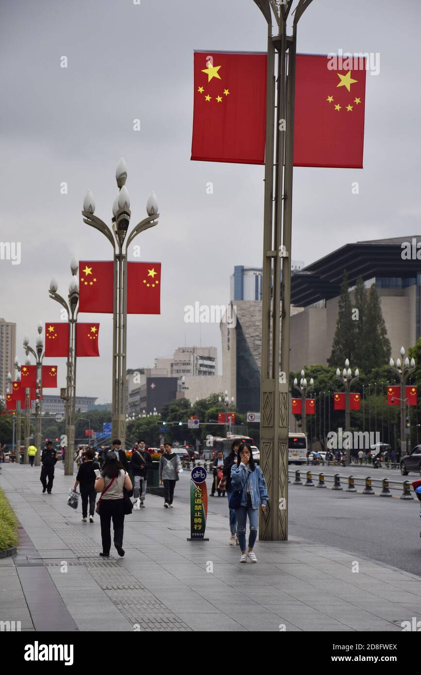 National flags fly on the street, under which vehicles and pedestrians ...