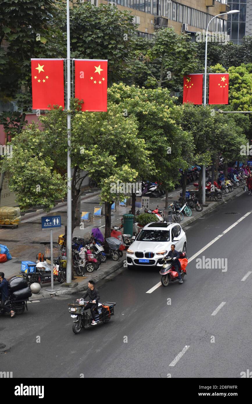 National flags fly on the street, under which vehicles and pedestrians ...