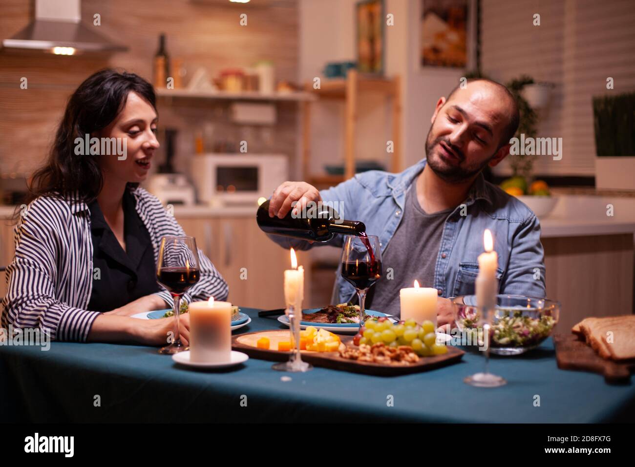 Husband pouring wife to wife during romantic dinner in dining room ...