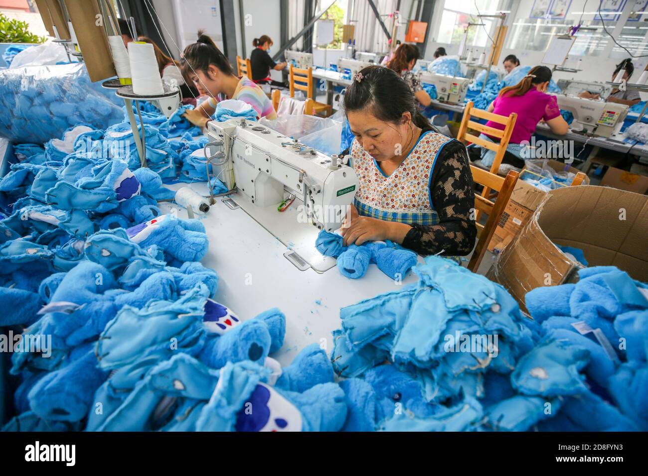 Workers are busy with the production in a large doll factory in Ankang ...