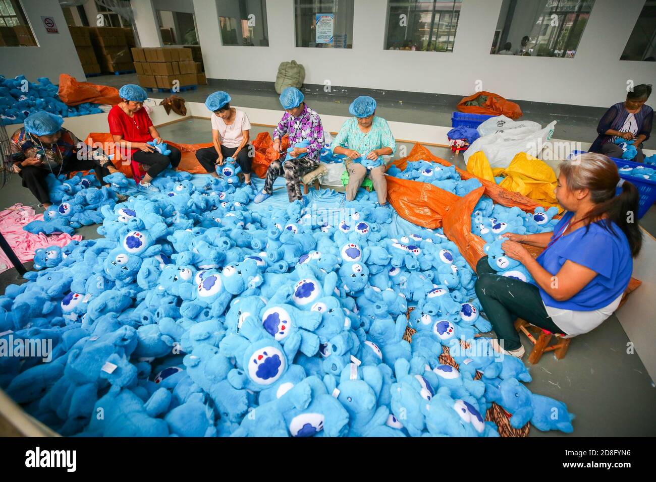 Workers are busy with the production in a large doll factory in Ankang ...