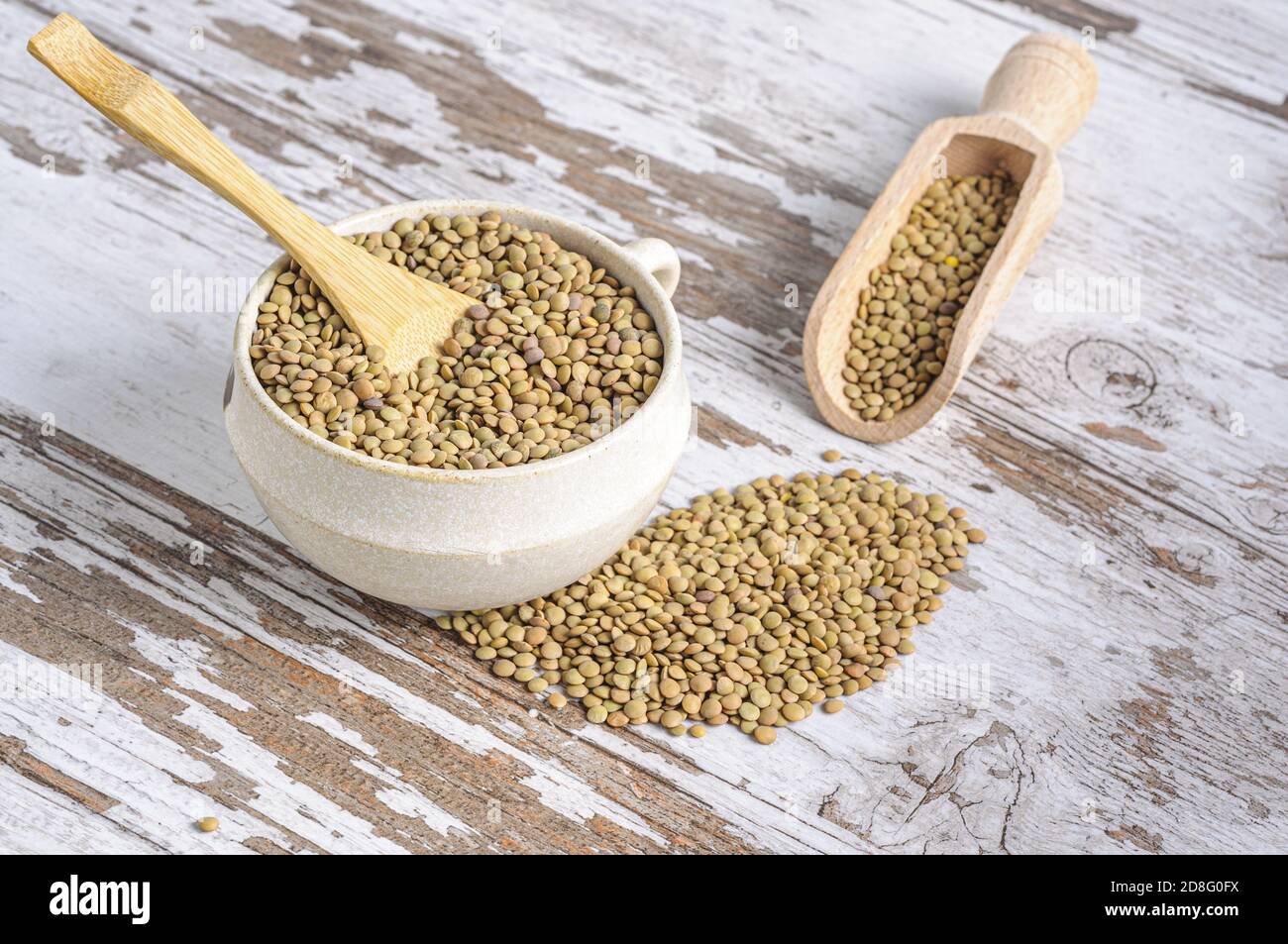 Closeup of dried lentil in a bowl with a wooden scoop on the table ...