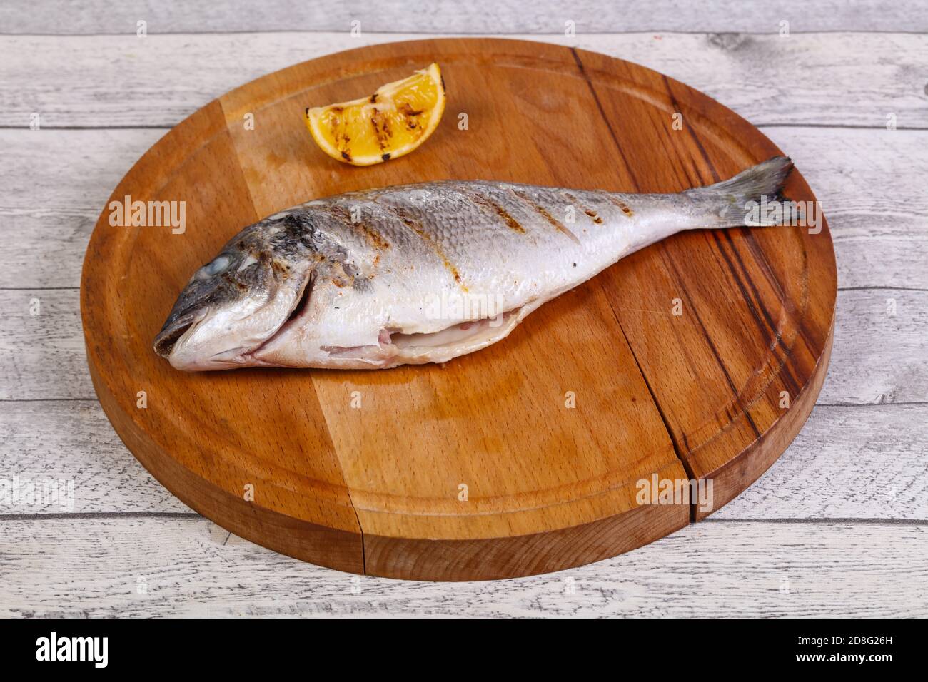 Grilled dorada with lemon over the wooden board Stock Photo - Alamy