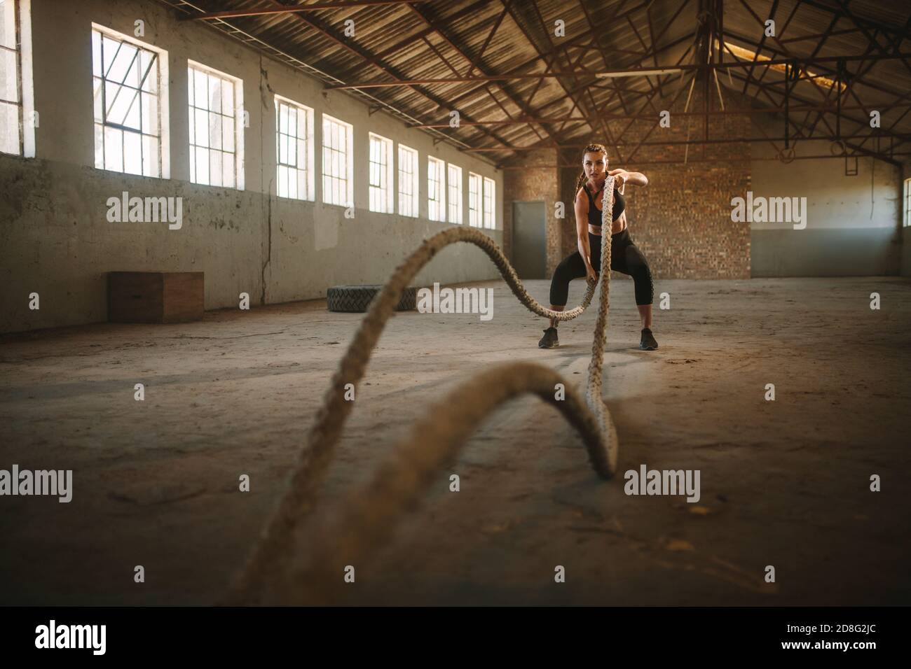 fitness woman workout with battle ropes inside abandoned warehouse ...