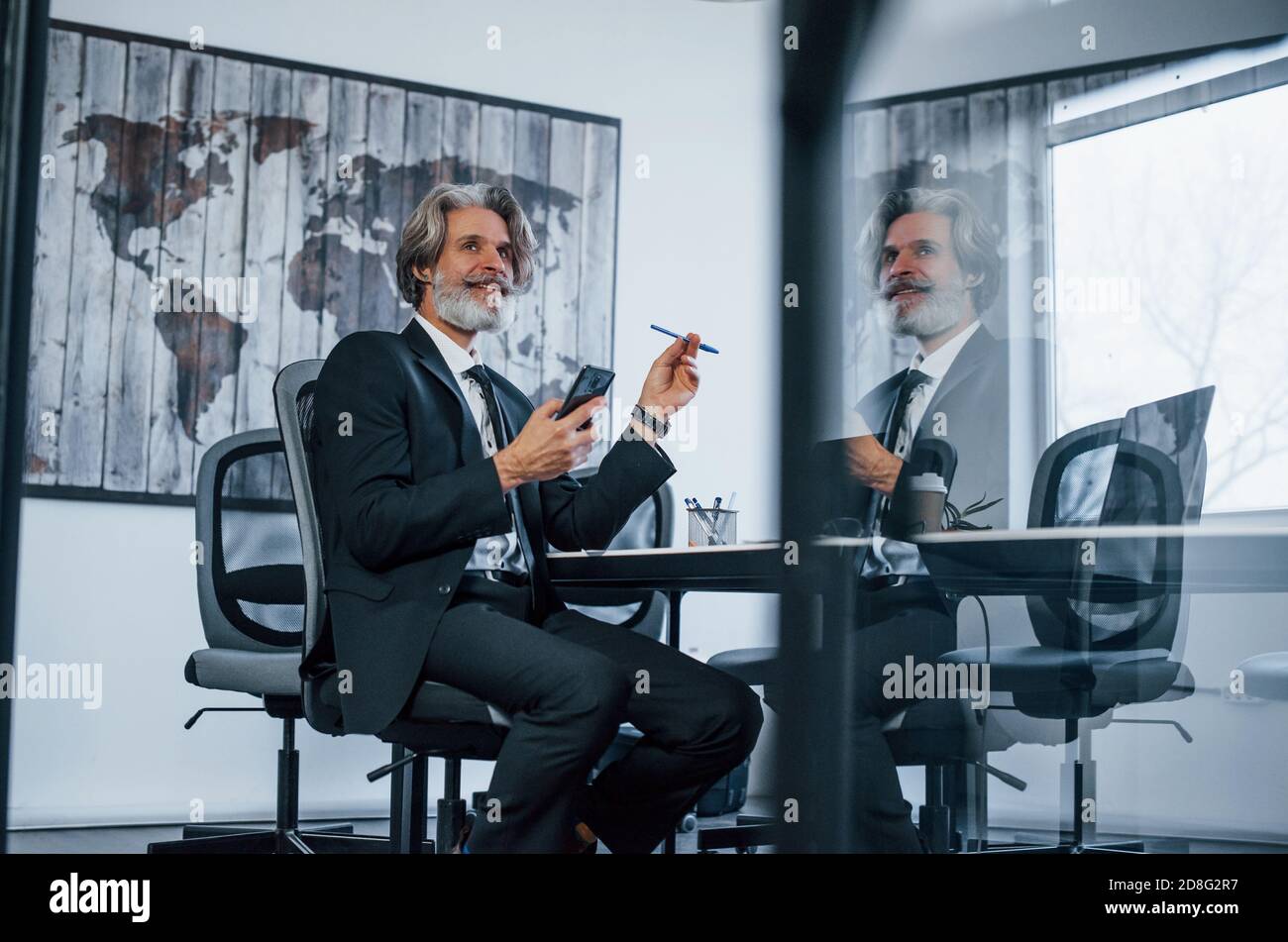 Mature businessman with grey hair and beard in formal clothes is in the ...