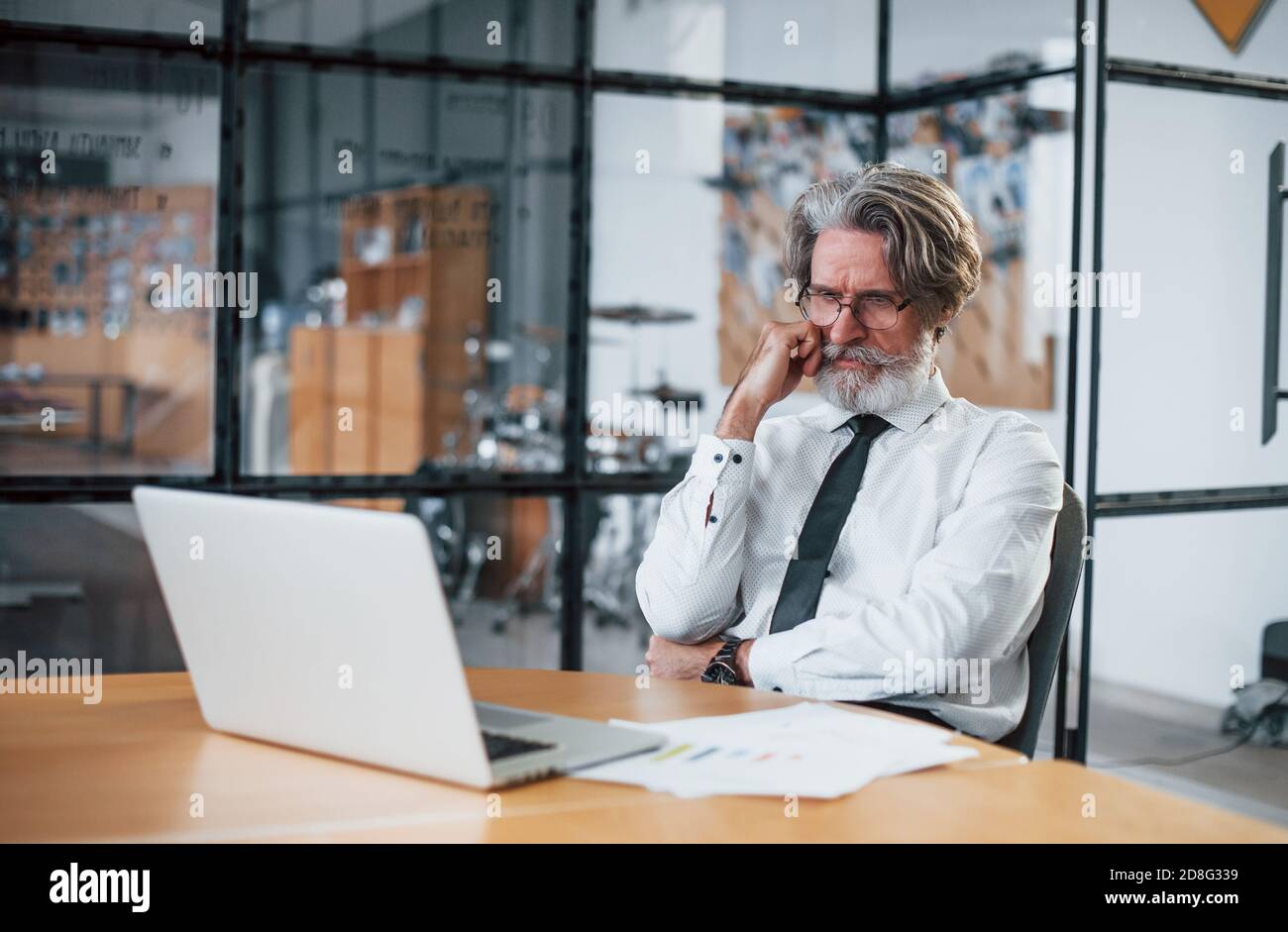 Bored mature businessman with grey hair and beard in formal clothes is ...