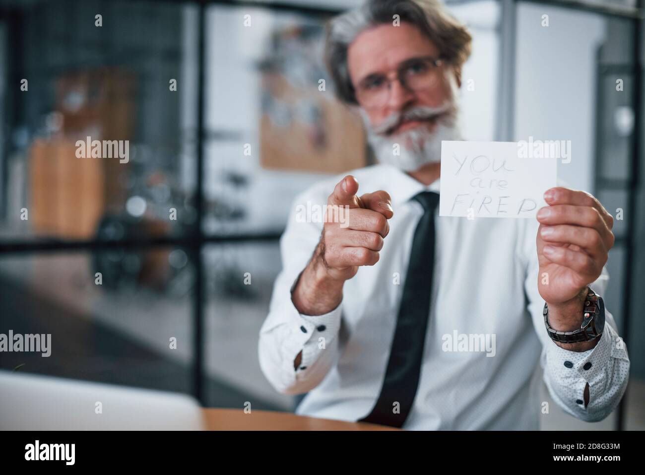 Holding paper with text you are fired. Mature businessman with grey ...