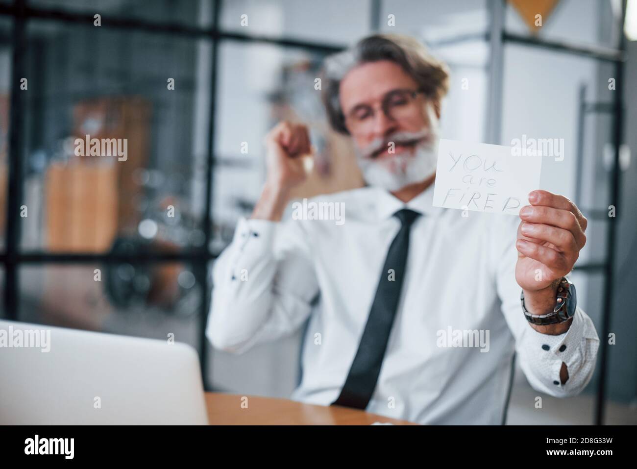 Holding paper with text you are fired. Mature businessman with grey ...
