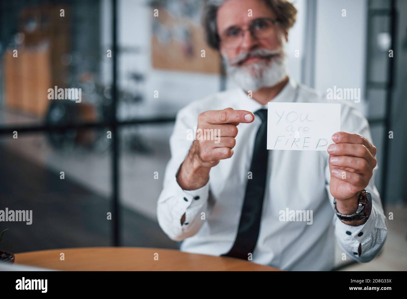 Holding paper with text you are fired. Mature businessman with grey ...