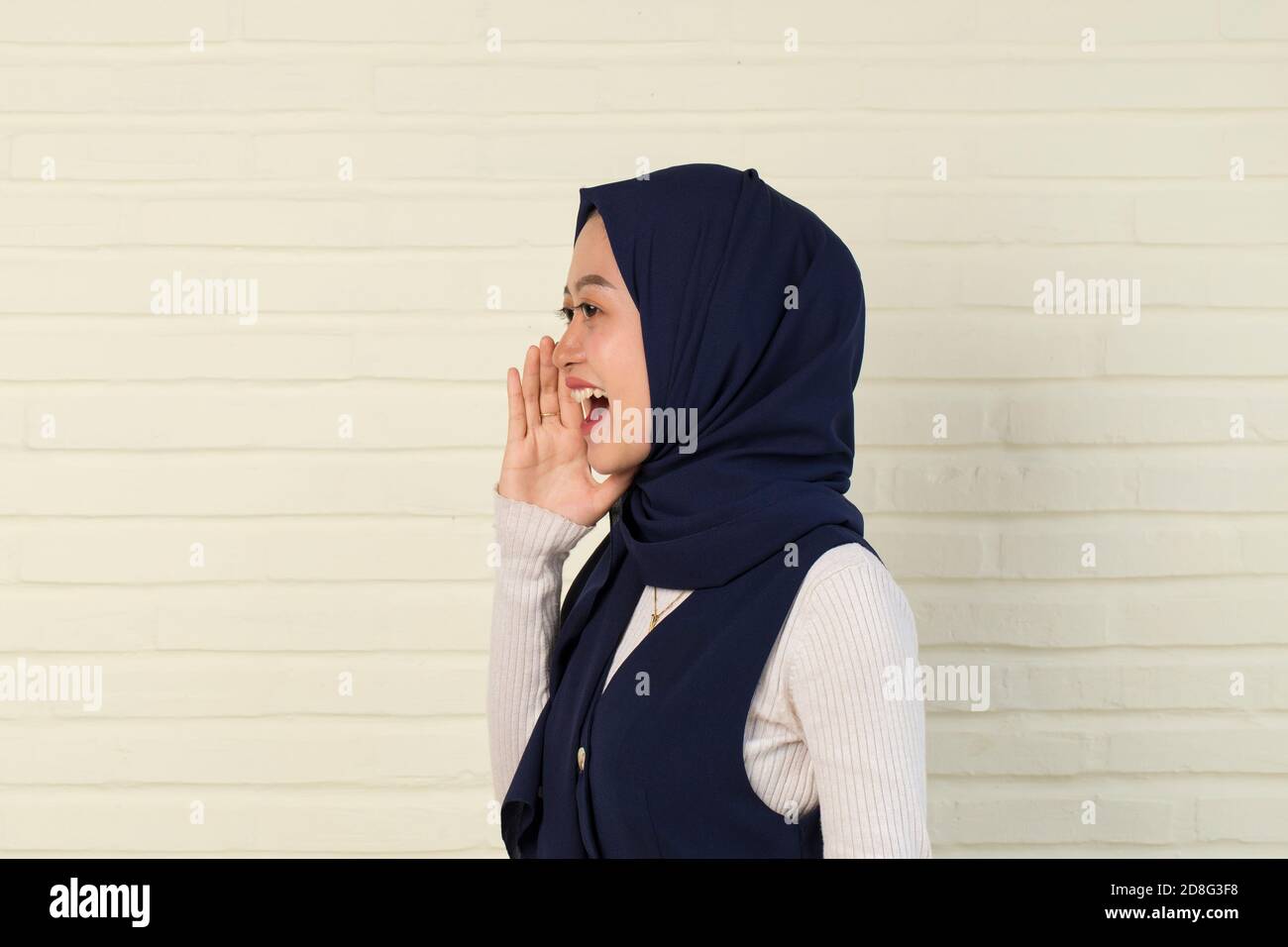 Portrait of young Asian muslim woman wearing hijab shouting and yelling ...