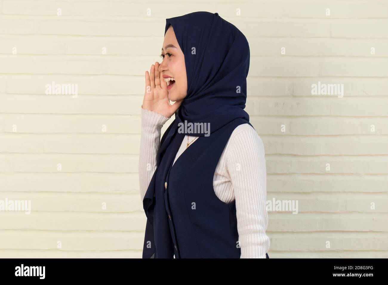 Portrait of young Asian muslim woman wearing hijab shouting and yelling ...