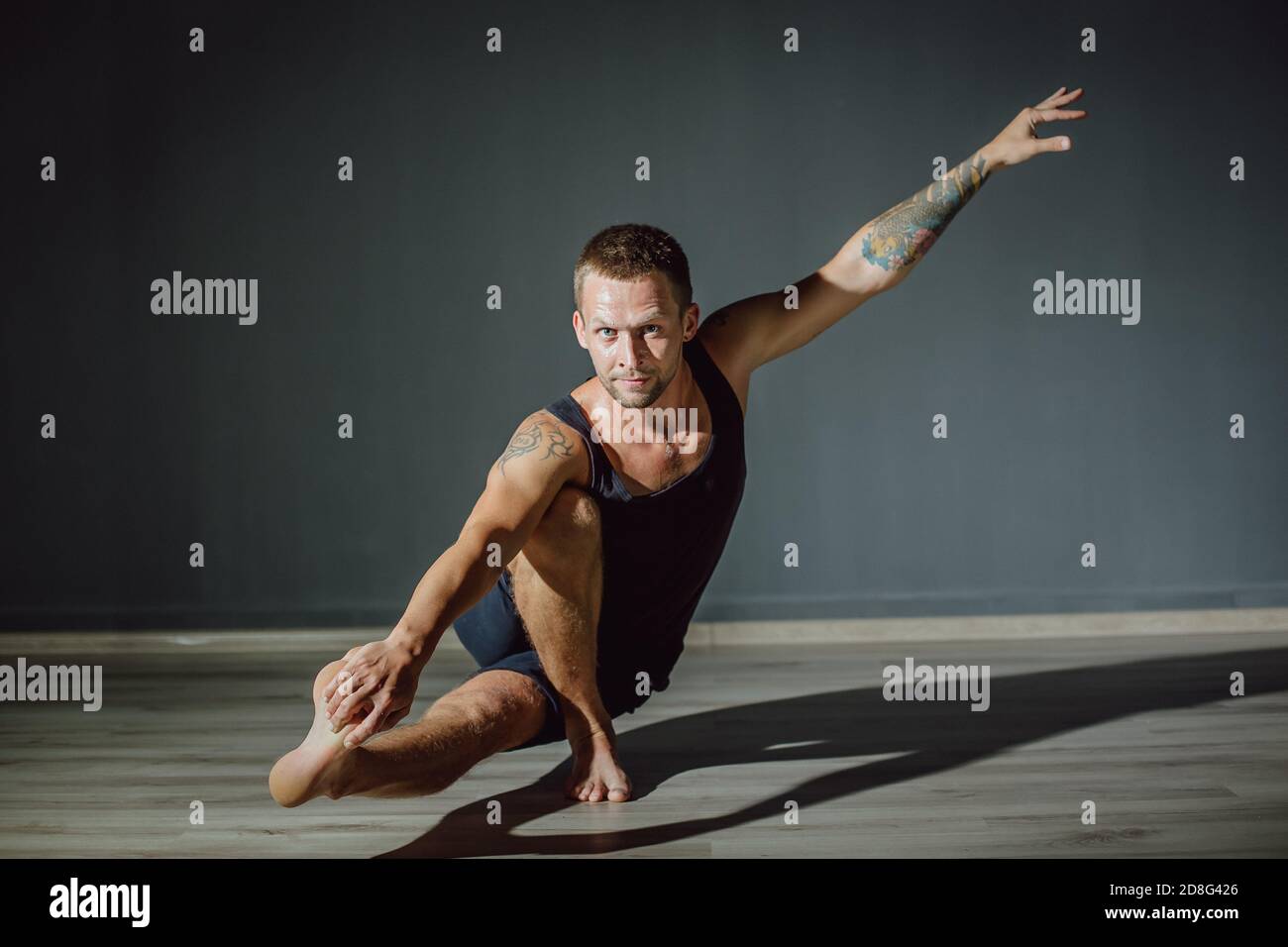 A man sits on one leg and holds the other with his hand. Balance pose ...