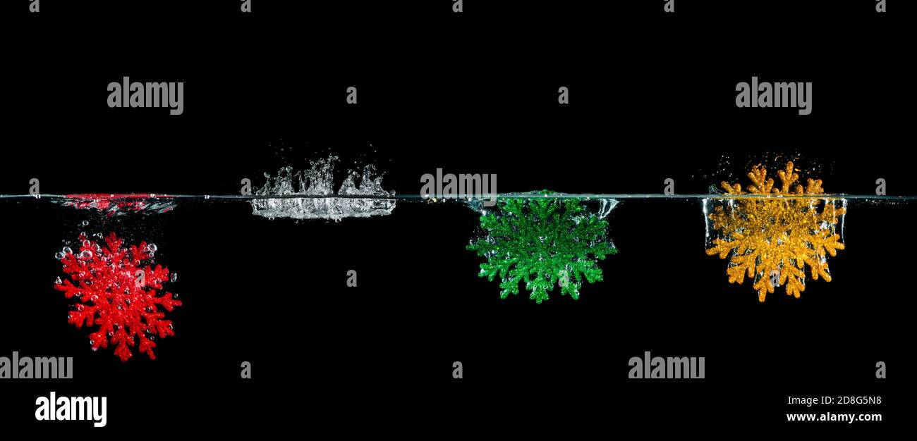 colorful holiday snowflakes splash in water at black background Stock ...