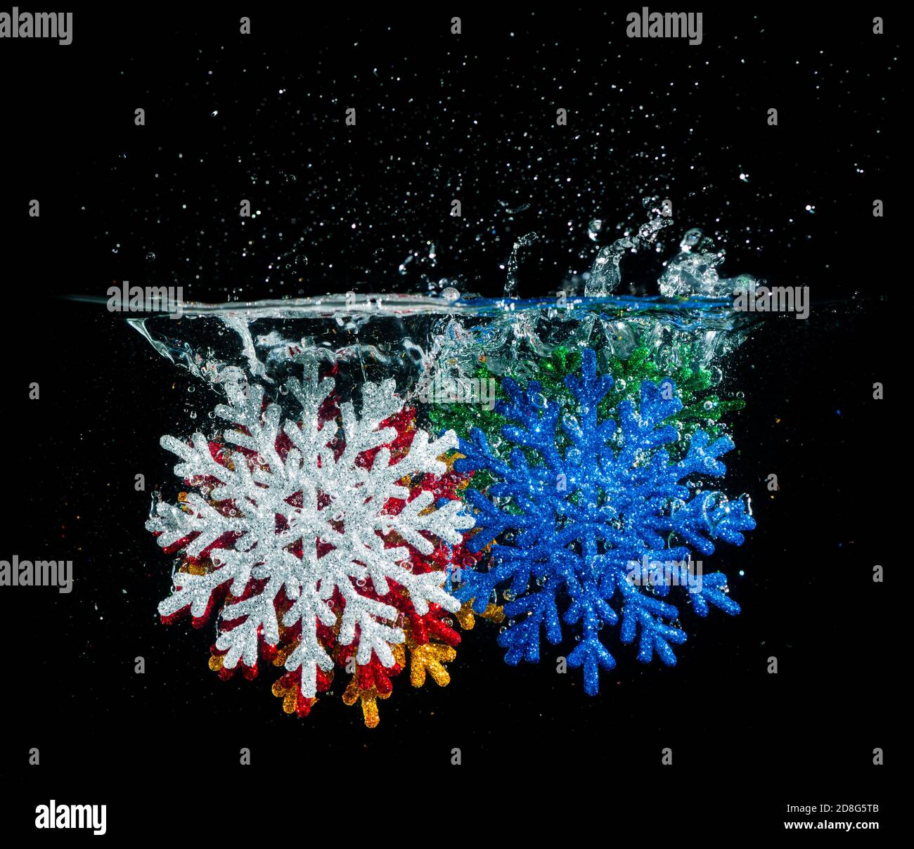 colorful holiday snowflakes splash in water at black background Stock ...