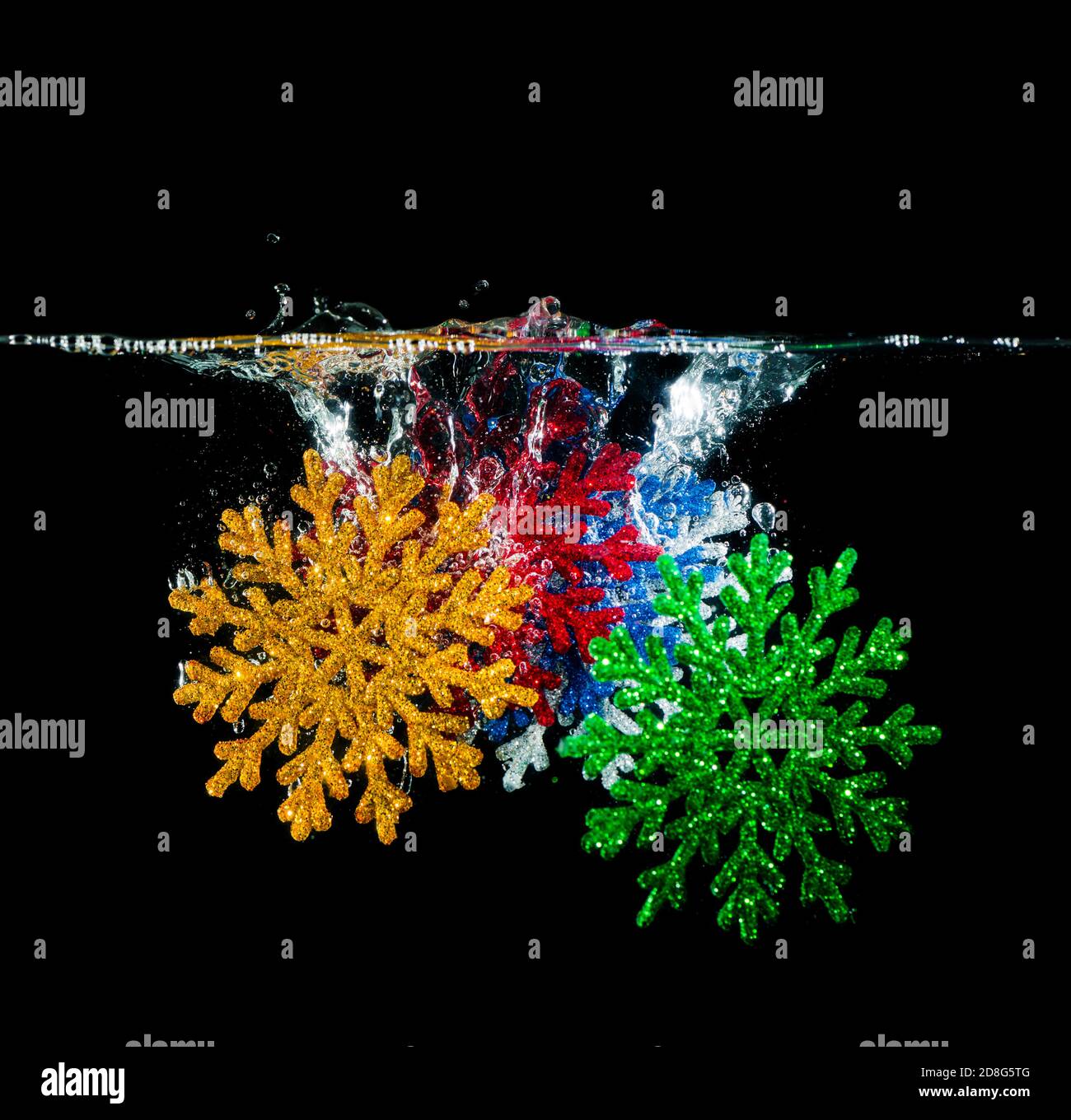 colorful holiday snowflakes splash in water at black background Stock ...