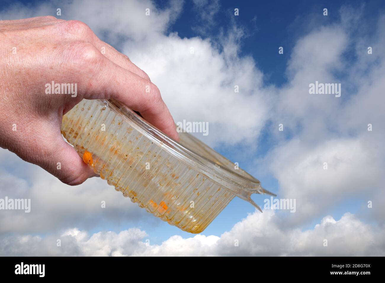 A female hand holds a dirty plastic container for food products against ...