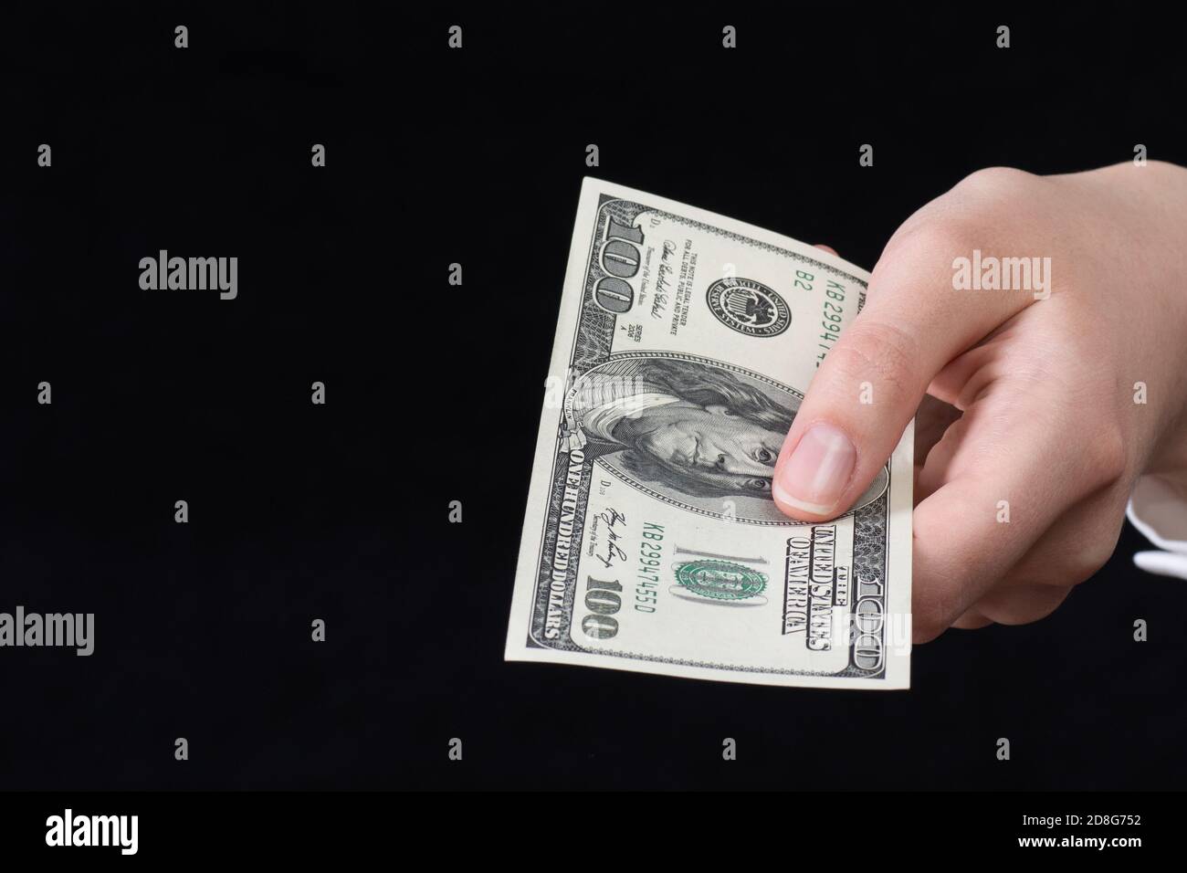 Female hand in a white shirt holds and shows one hundred dollar bill in ...