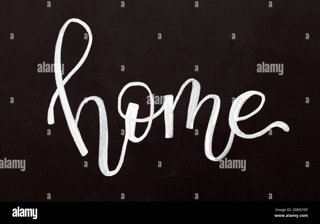 Chalk inscription HOME on a black chalkboard. Handwritten lettering ...