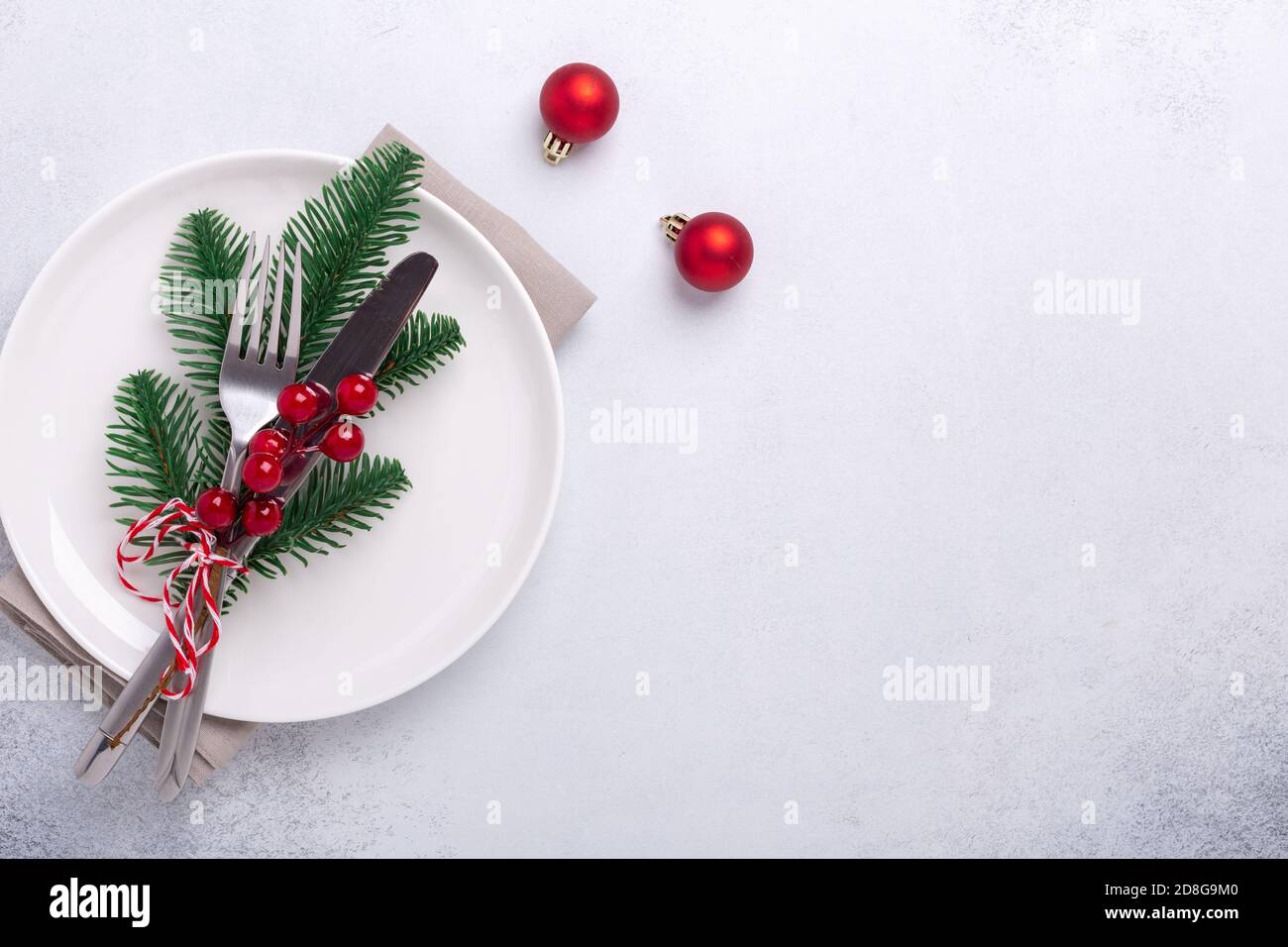 Christmas table place setting with empty white plate, candy canes, fir ...