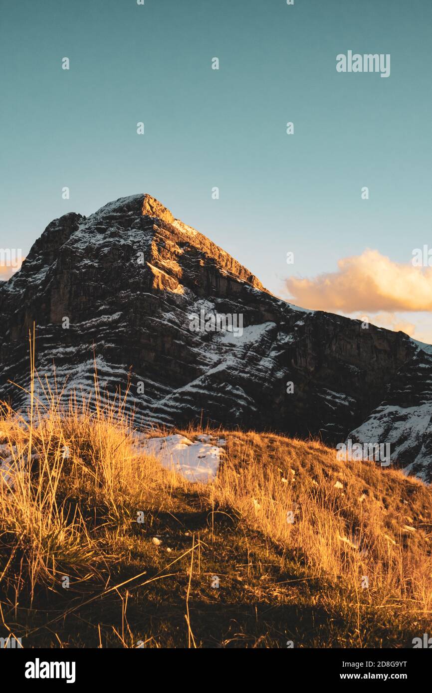 A dry sunlit landscape with a rugged immense rock formation covered ...