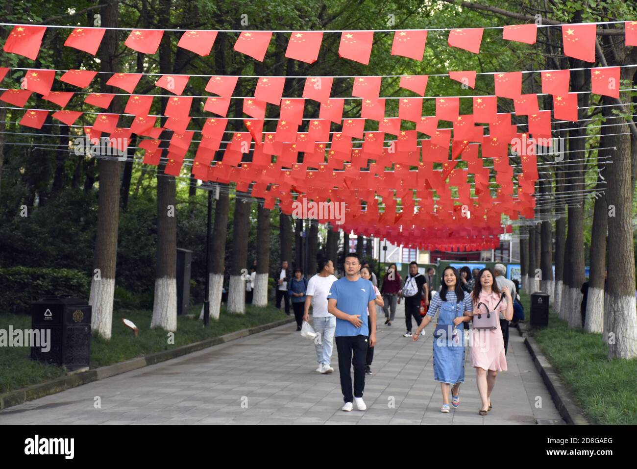 National flags fly on the street, under which vehicles and pedestrians ...