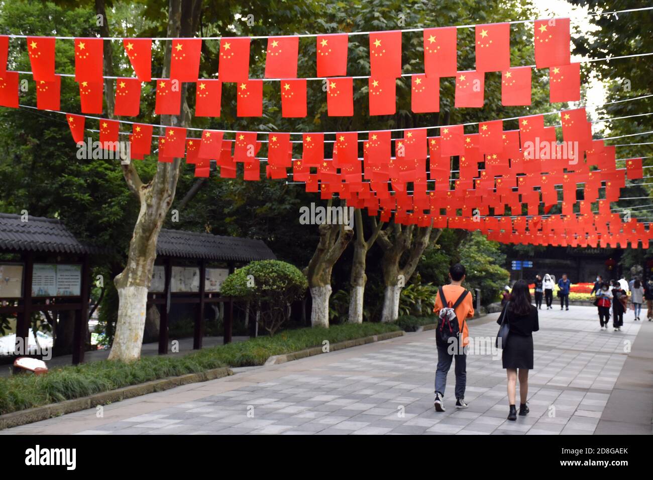 National flags fly on the street, under which vehicles and pedestrians ...