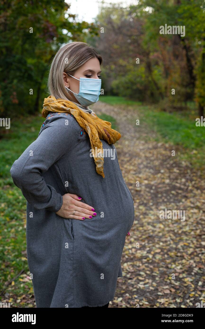 Beautiful pregnant woman in the park wearing surgical mask because of ...