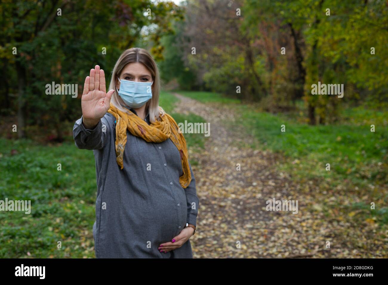 Beautiful pregnant woman in the park wearing surgical mask because of ...