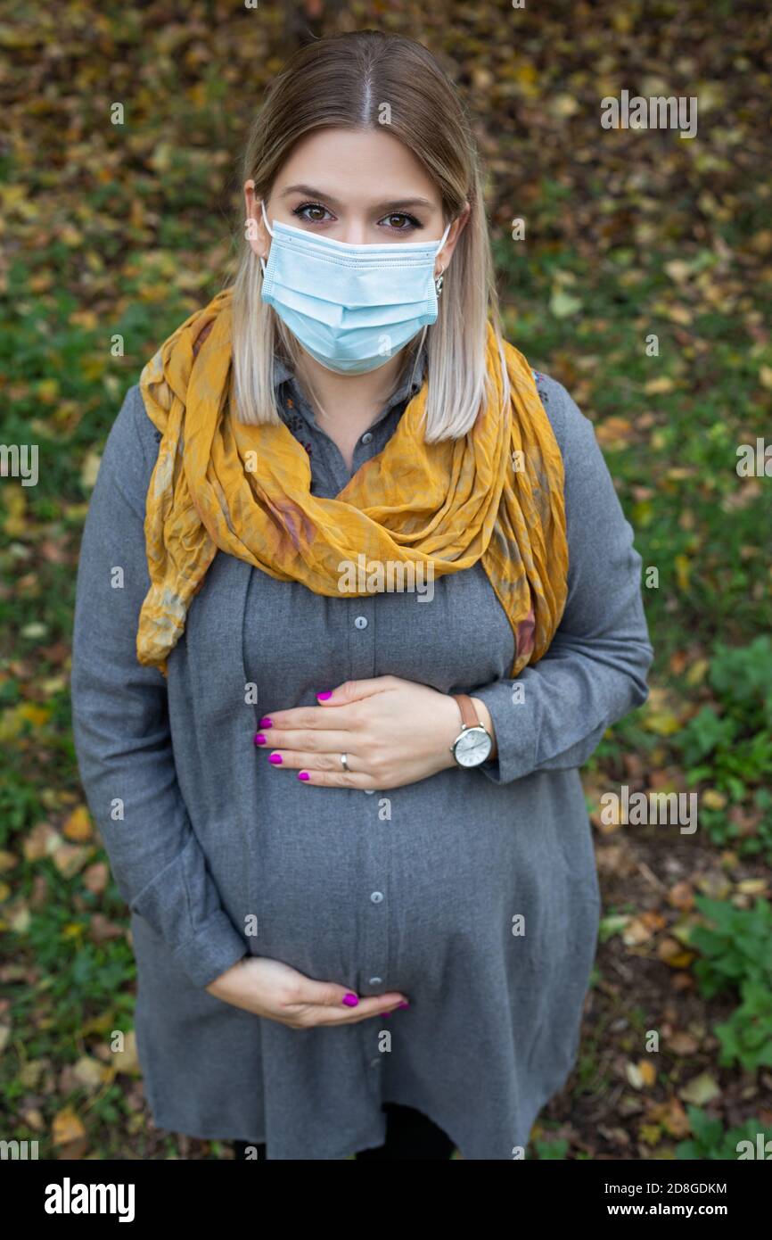 Beautiful pregnant woman in the park wearing surgical mask because of ...