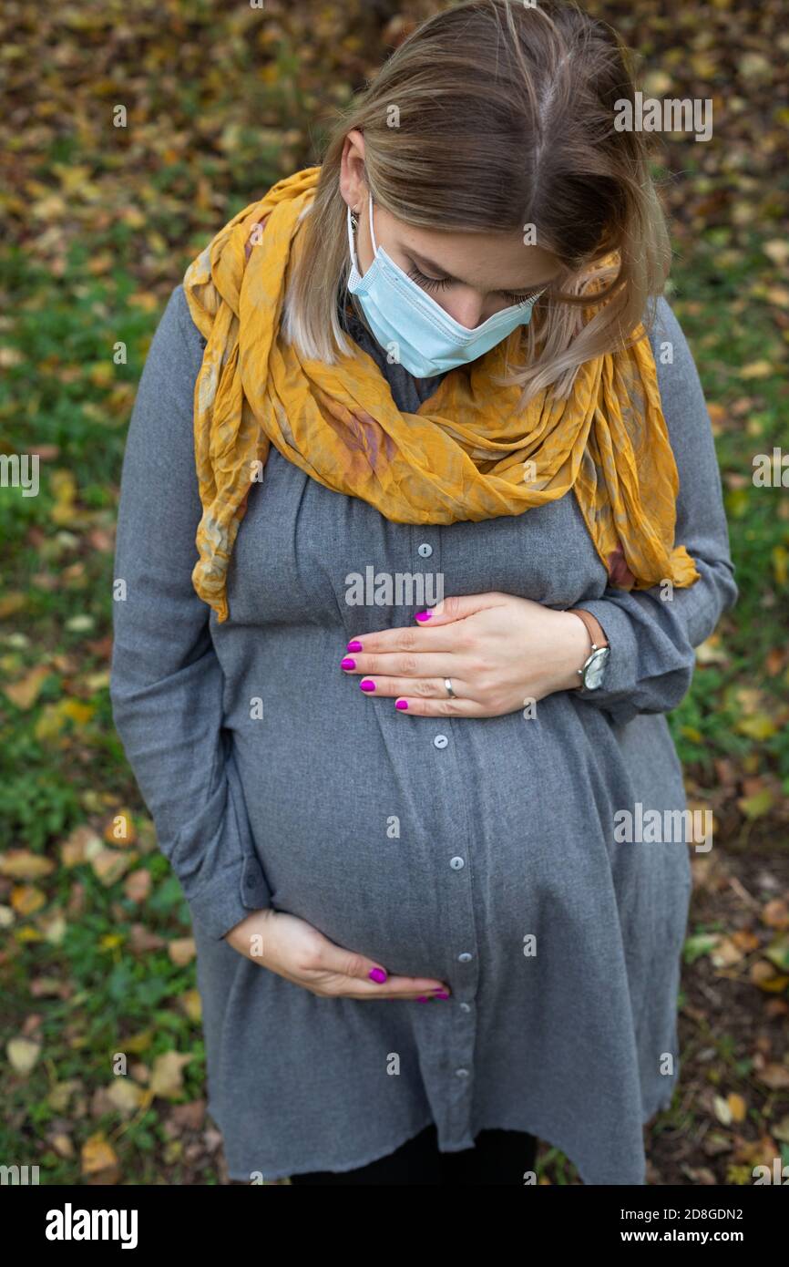 Beautiful pregnant woman in the park wearing surgical mask because of ...