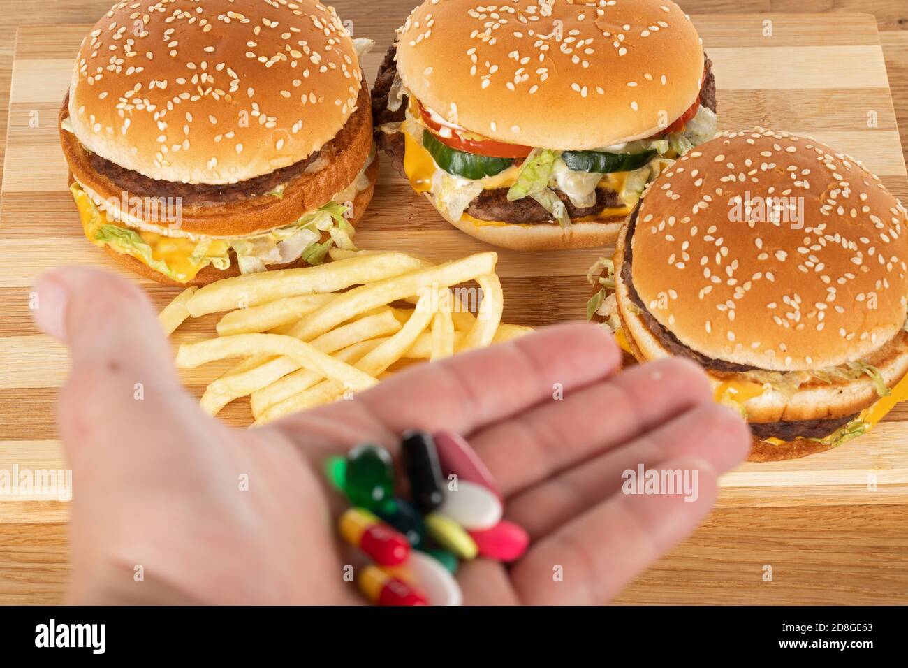 Close up picture of human hand holding pills , burgers and fries in the ...