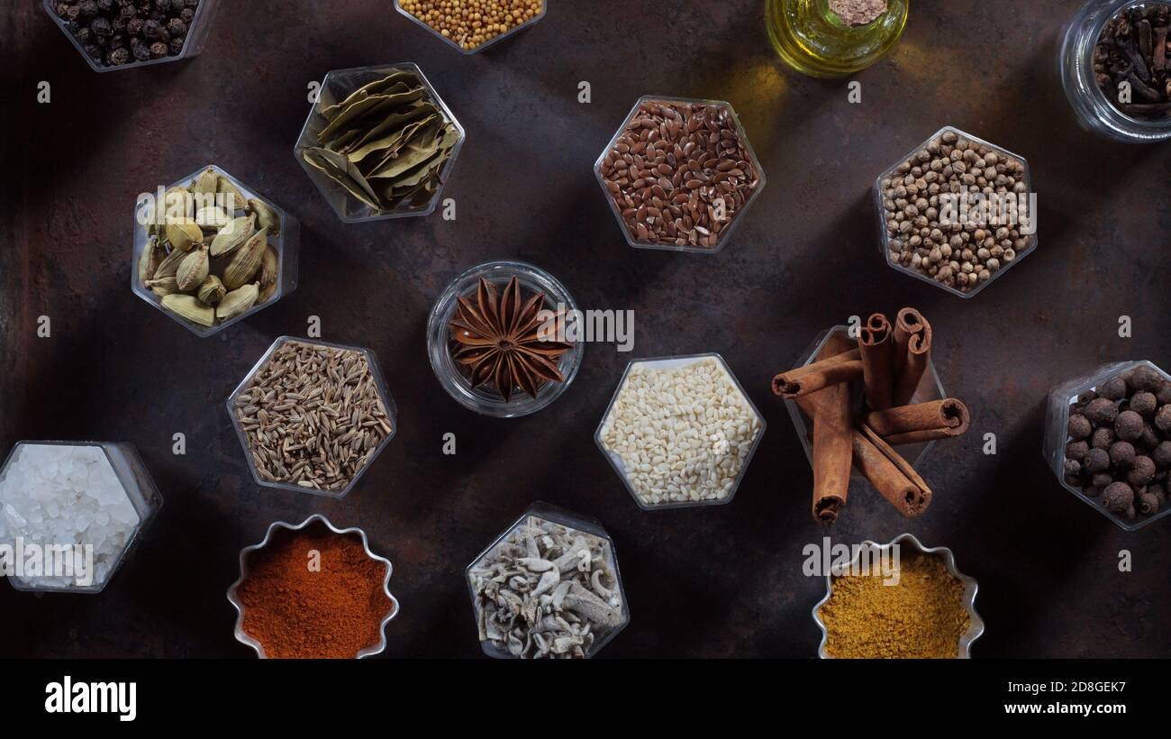 Various spices in hexagonal jars appear on a metal rusty baking sheet ...