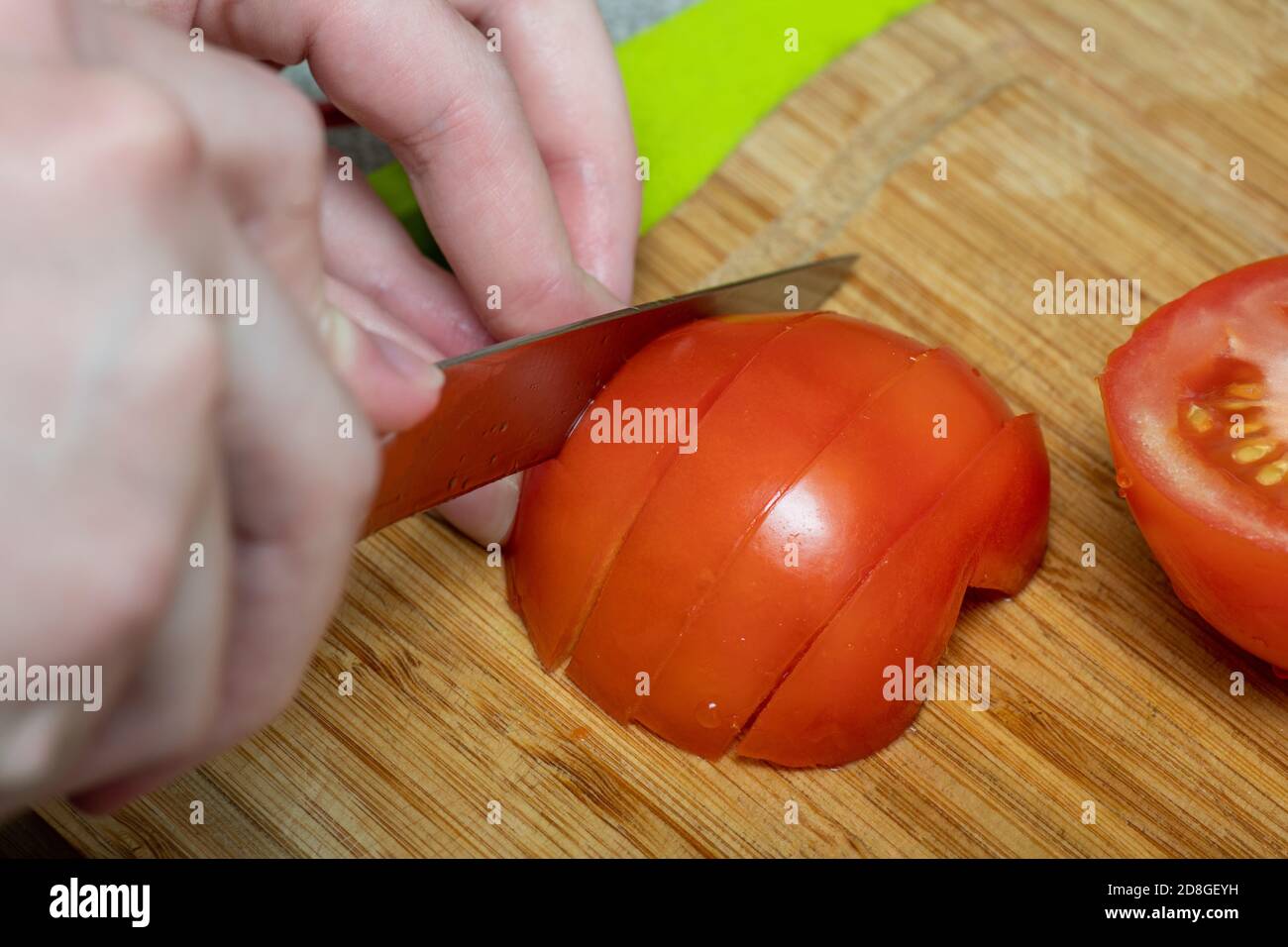 close-up top view female hands cut tomato for making salad. Healthy and ...