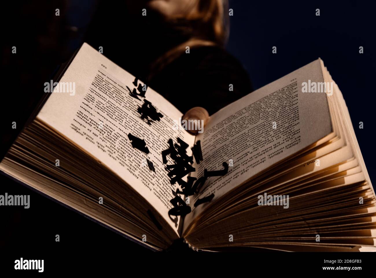 Person holding an open book with letters falling out Stock Photo - Alamy
