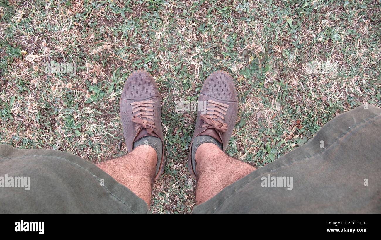 Young man in his short, with his shoes standing on the green grass soil ...