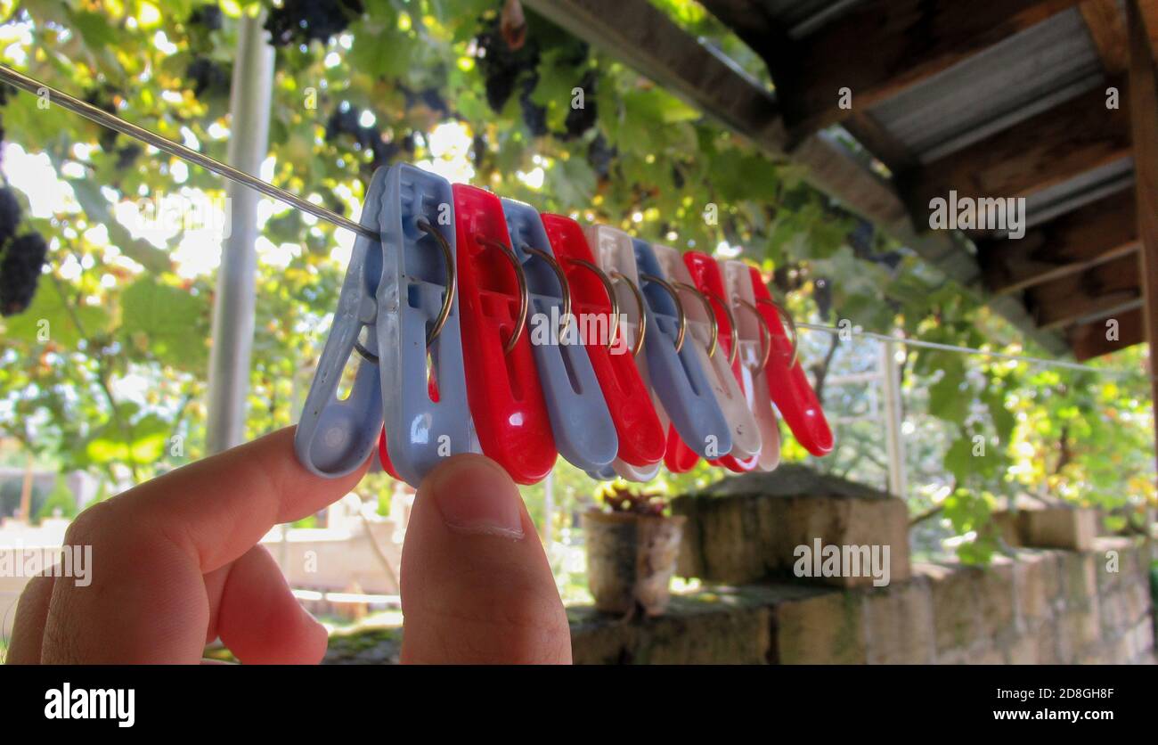 A close up of a male hand holding clothes pins on a clothes line rope ...