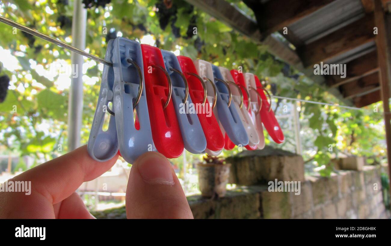 A close up of a male hand holding clothes pins on a clothes line rope ...