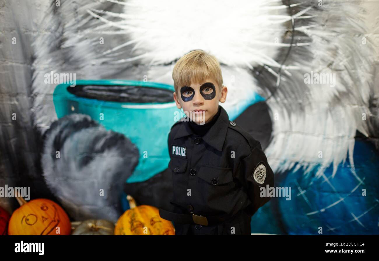 Portrait of a cute funny kid in police costume posing on the street ...