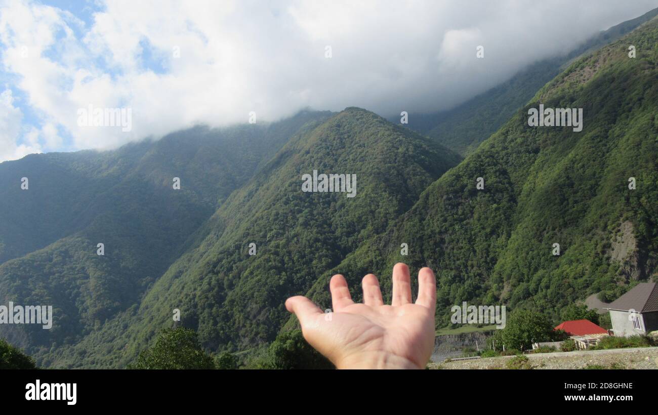 Close up young male, man hand showing big green Caucasian mountains and ...