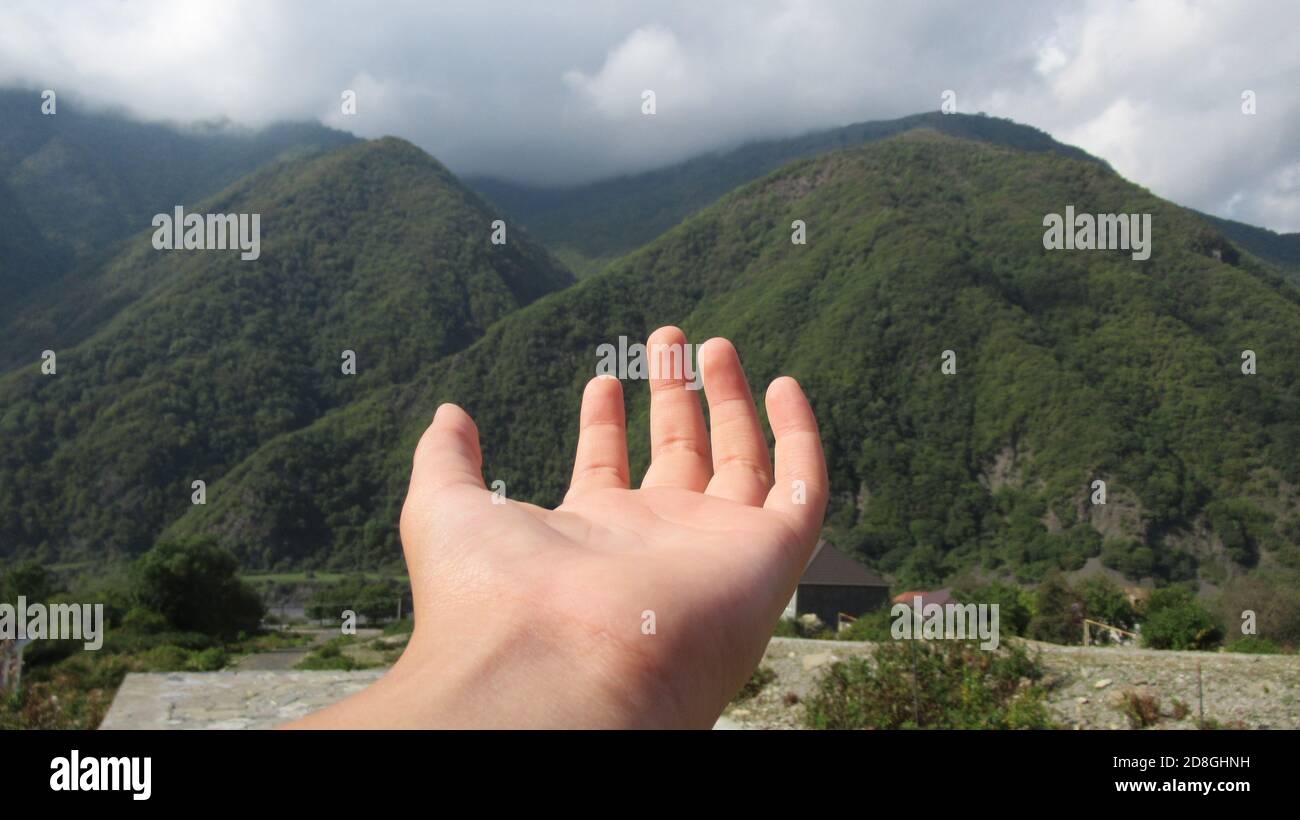 Close up young male, man hand showing big green Caucasian mountains and ...